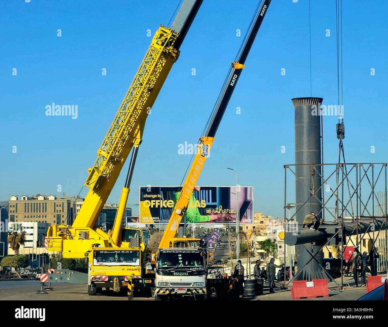 Cairo, Egypt, February 27 2025: mobile cranes fitting a steel structure advertising board in ...