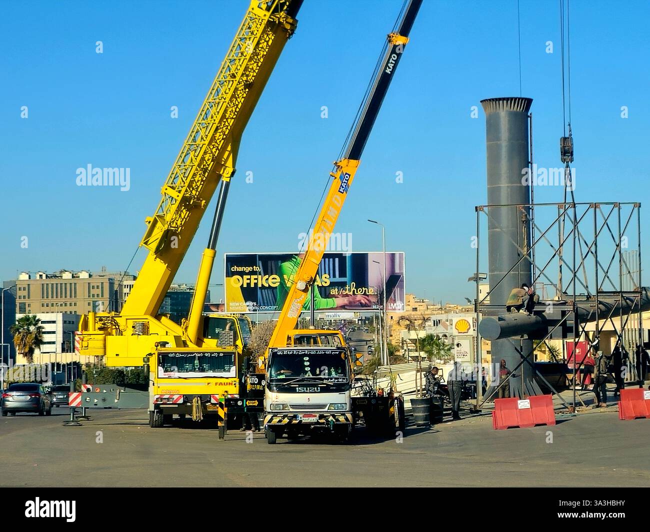 Cairo, Egypt, February 27 2025: mobile cranes fitting a steel structure advertising board in ...