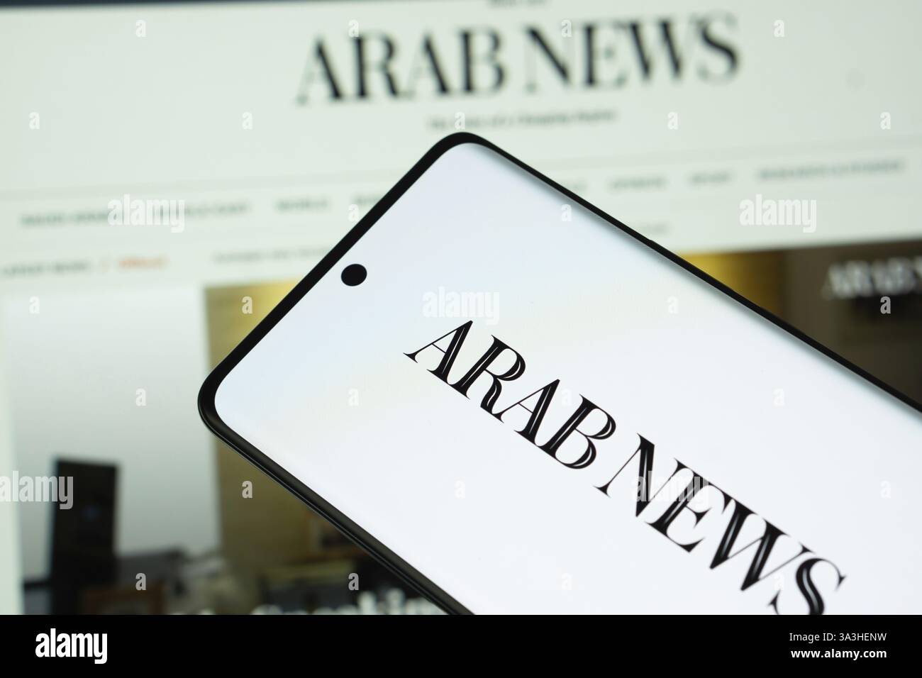 The logo of the ARAB NEWS is displayed on a smartphone screen, and the ...