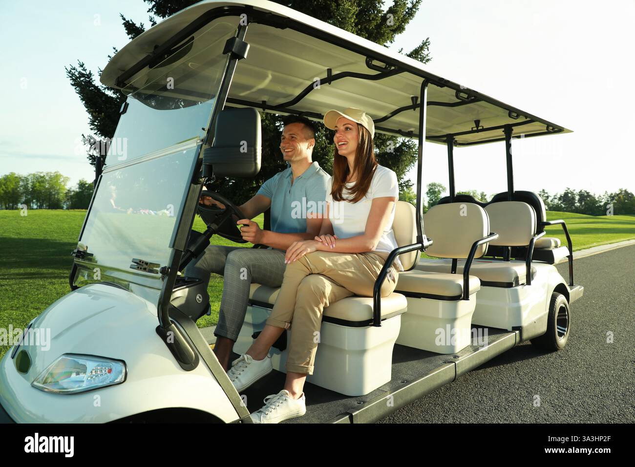 Happy couple driving golf cart on road in park Stock Photo - Alamy