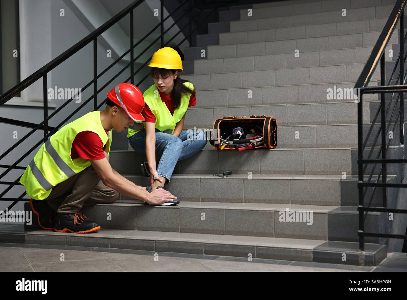 Accident at work. Man helping his injured colleague on stairs indoors ...