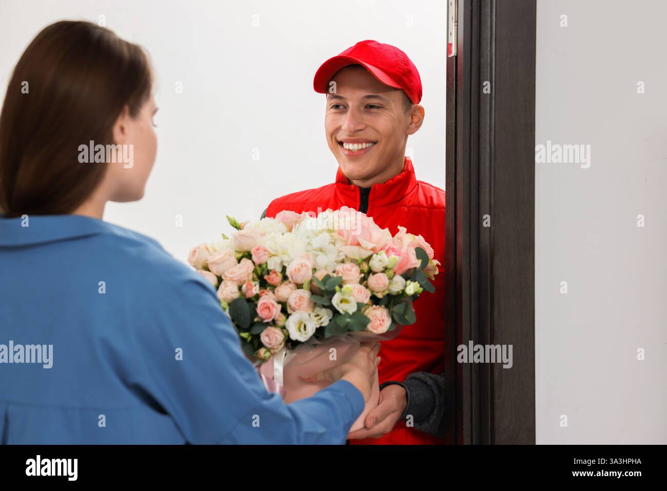 Smiling delivery man giving gift box with beautiful floral composition ...