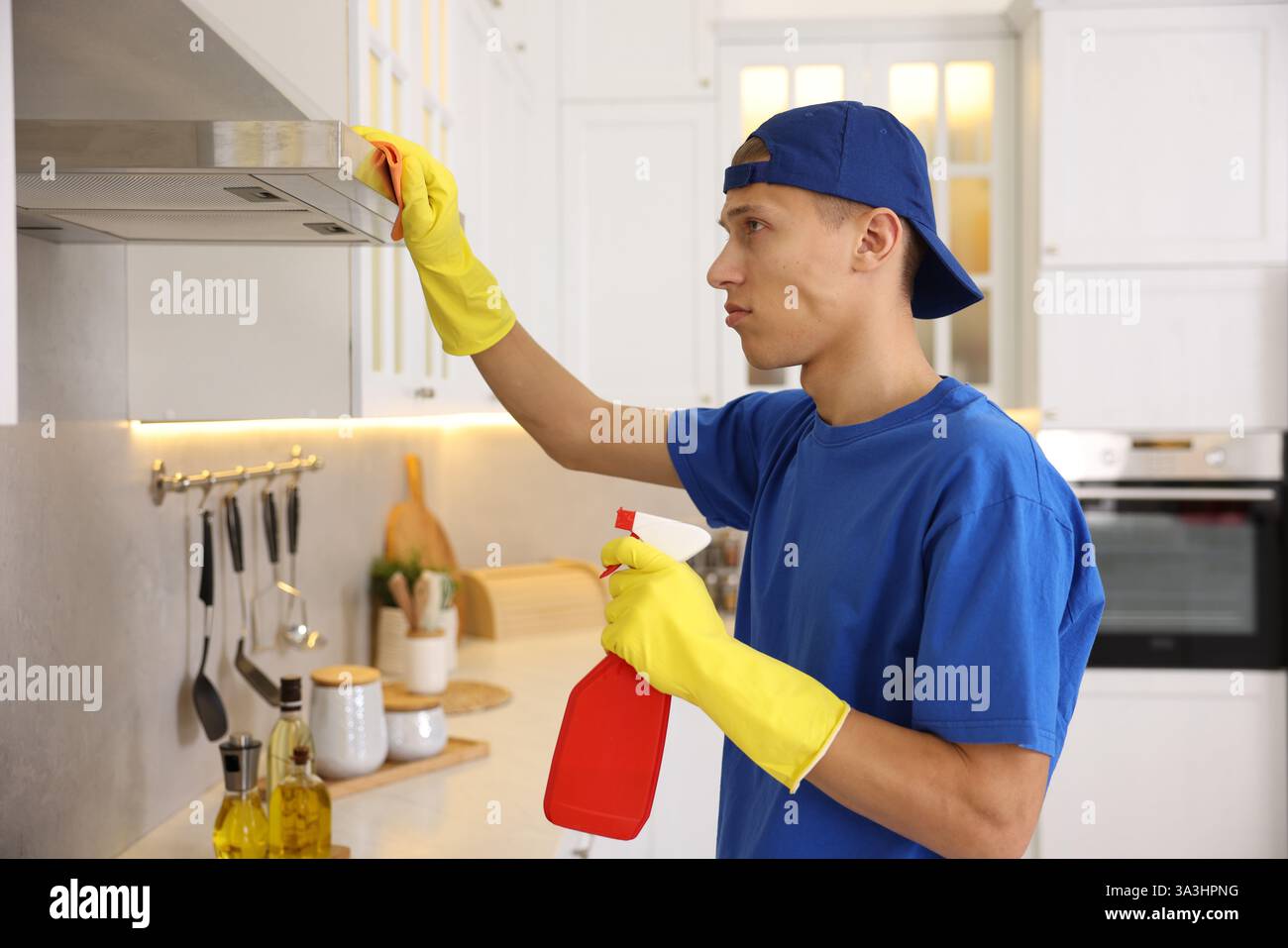 Professional janitor cleaning kitchen hood with rag and detergent ...