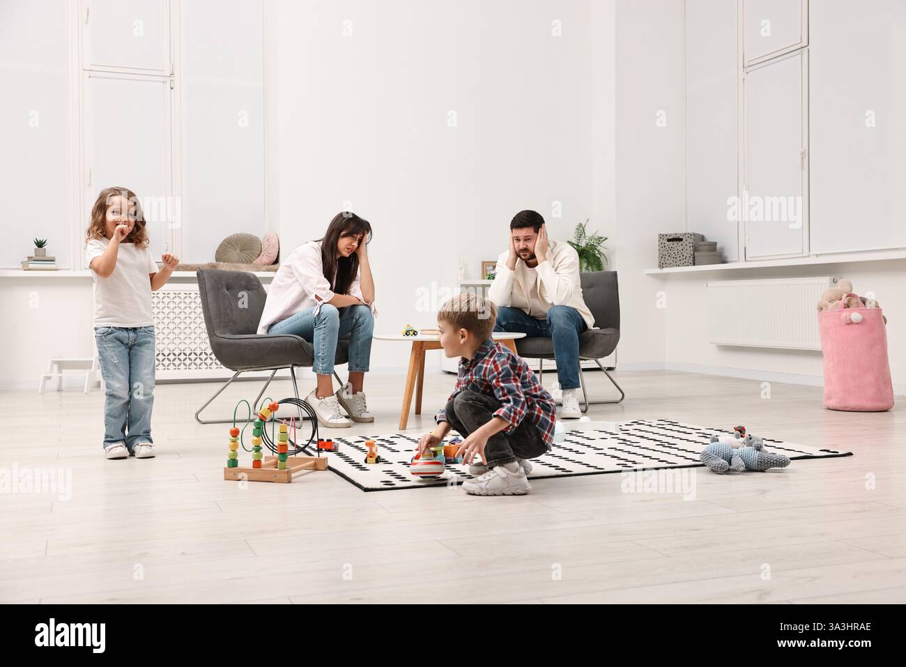 Hyperactive children playing and their overwhelmed parents at home ...