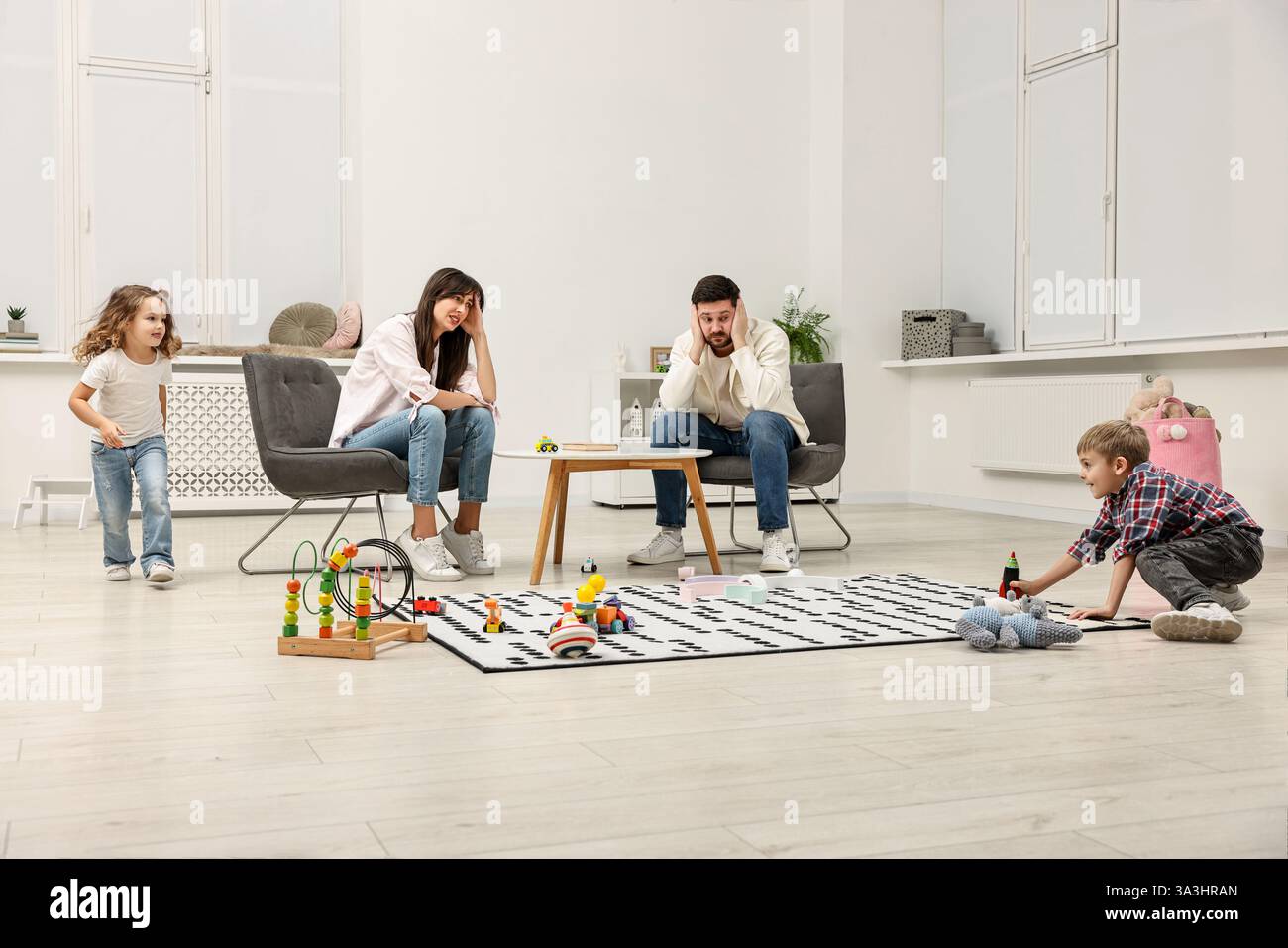 Hyperactive children playing and their overwhelmed parents at home ...