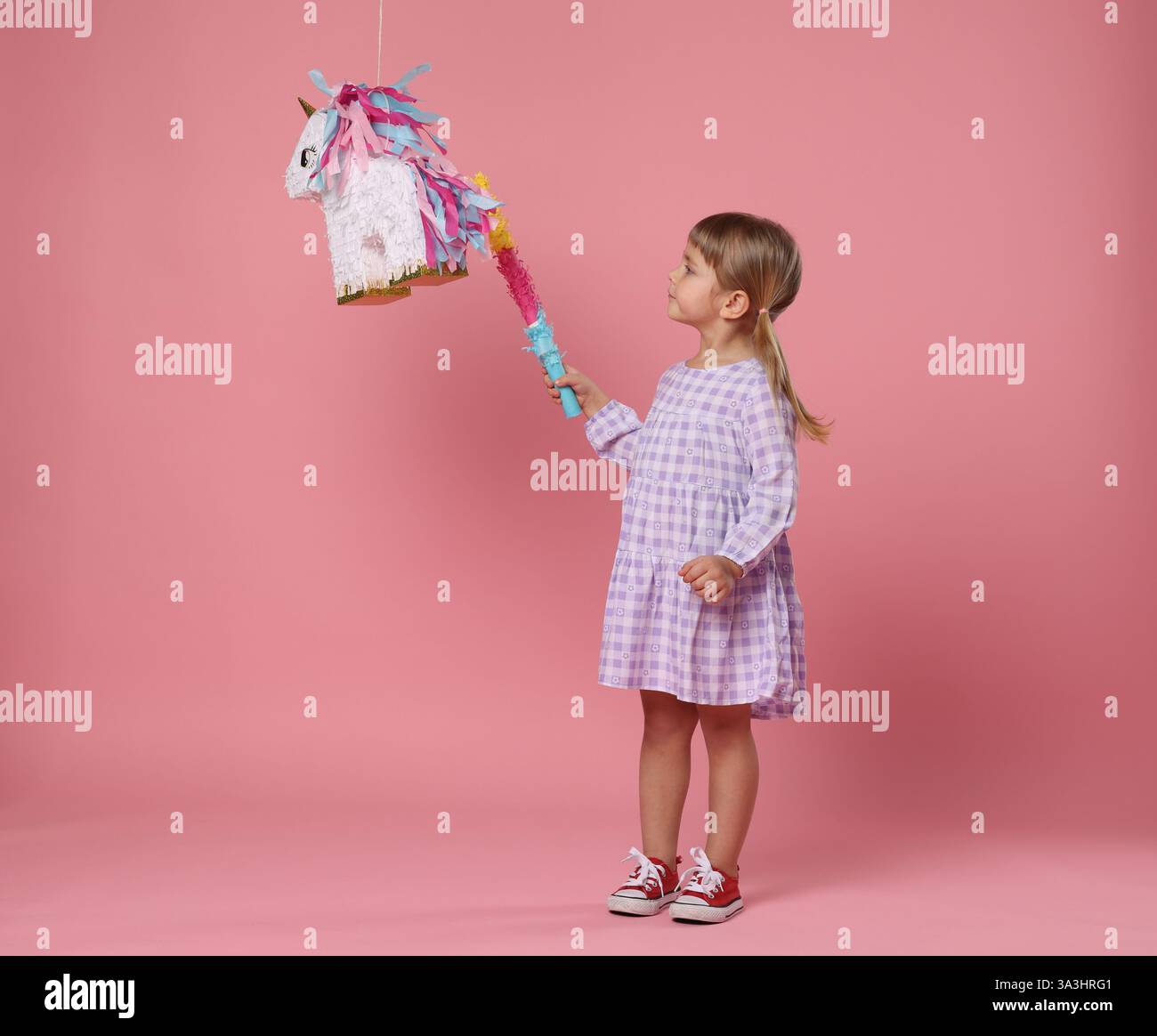 Cute girl with unicorn shaped pinata and stick on pink background Stock ...