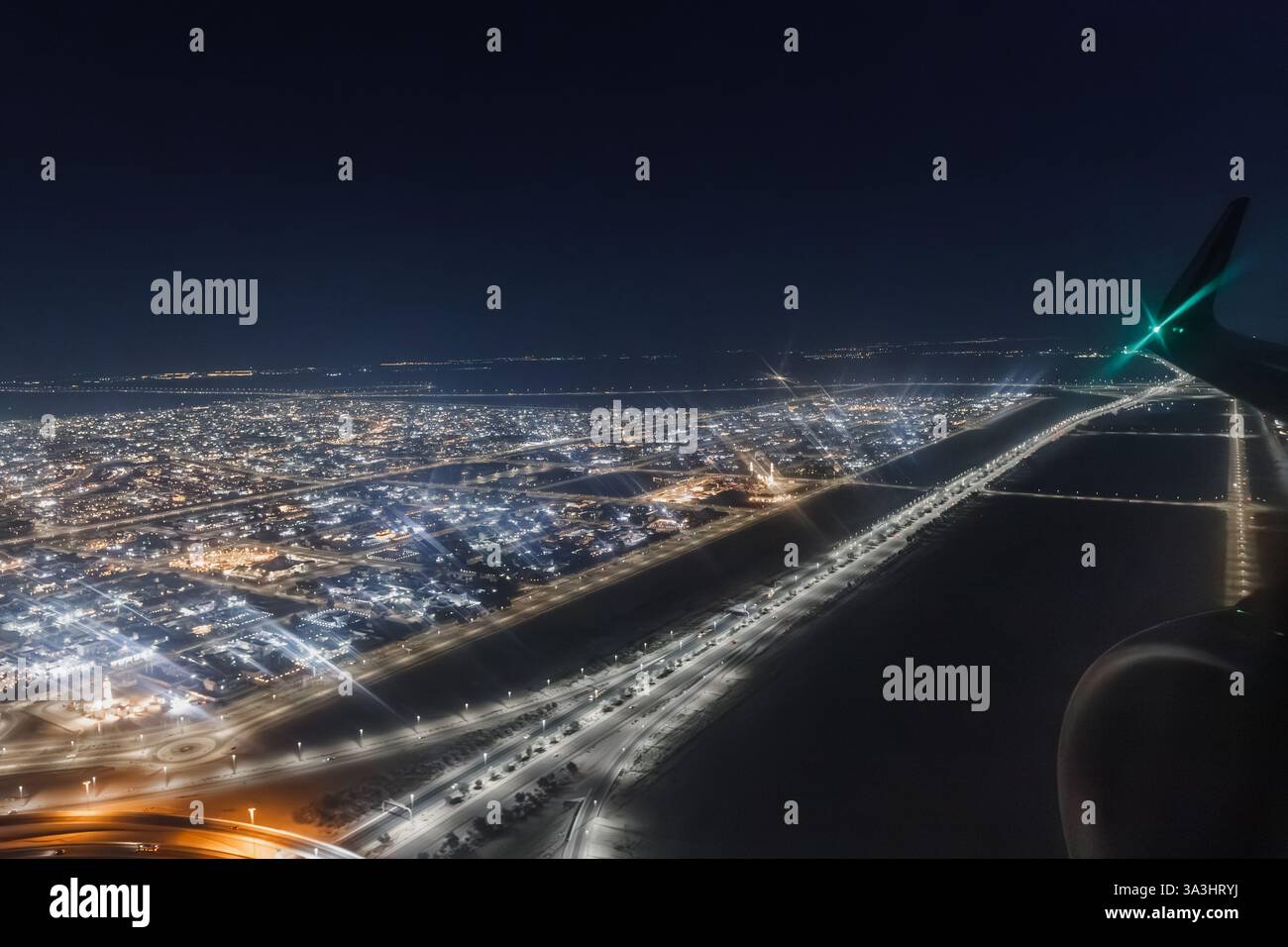 Airplane engine and wing flying over a big illuminated city at night ...