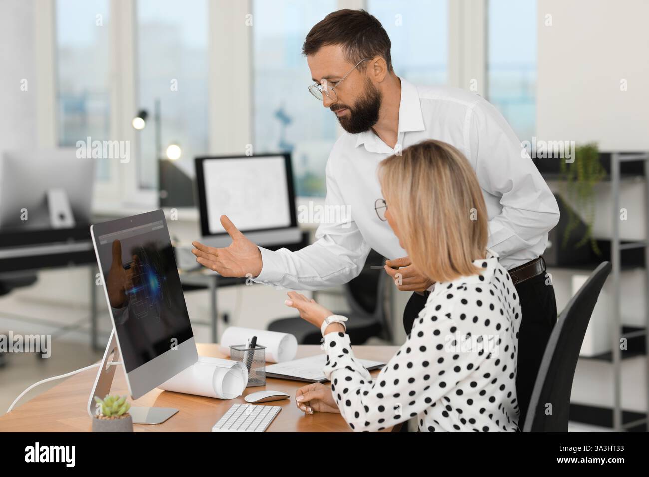 Technicians making digital engineering drawing on computer at desk in ...