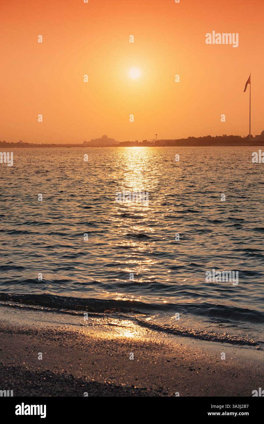 Golden sunset reflecting on calm sea waves washing sandy beach with ...