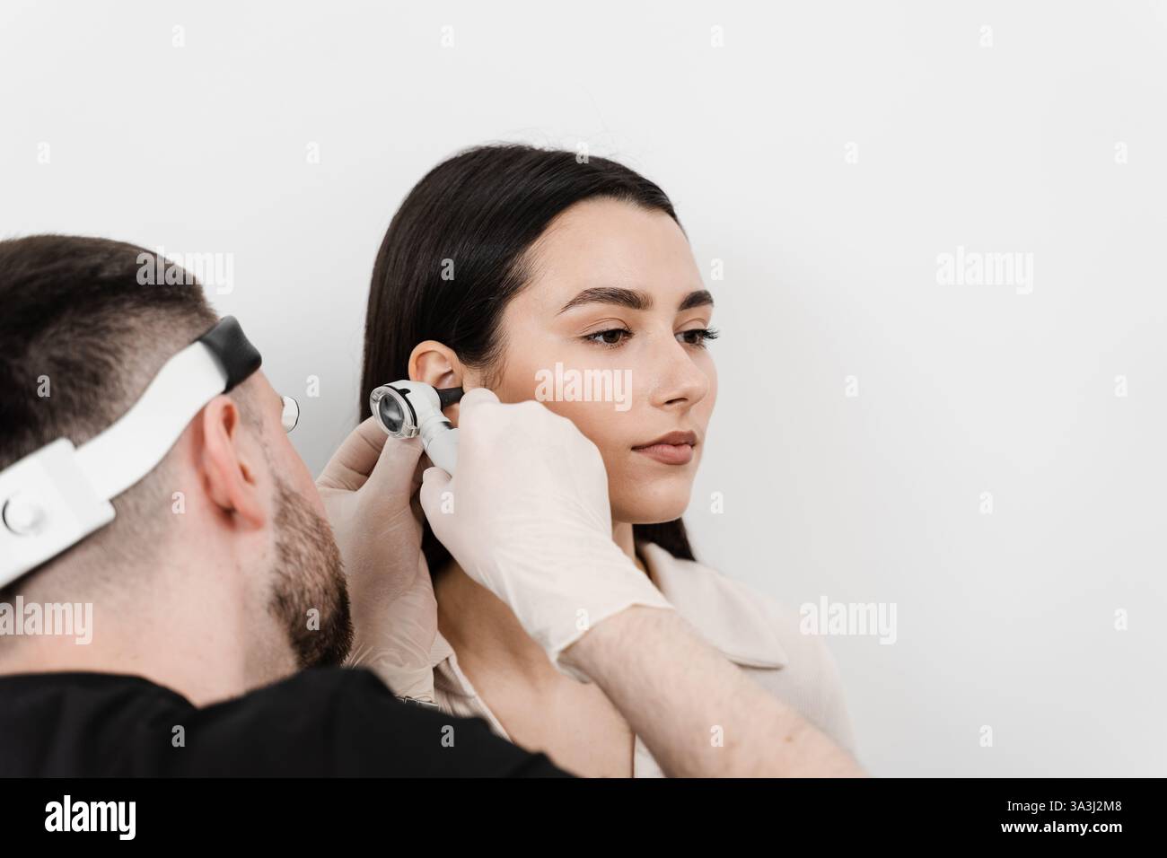 Otoscopy. Otolaryngologist is looking through otoscope the ears of ...