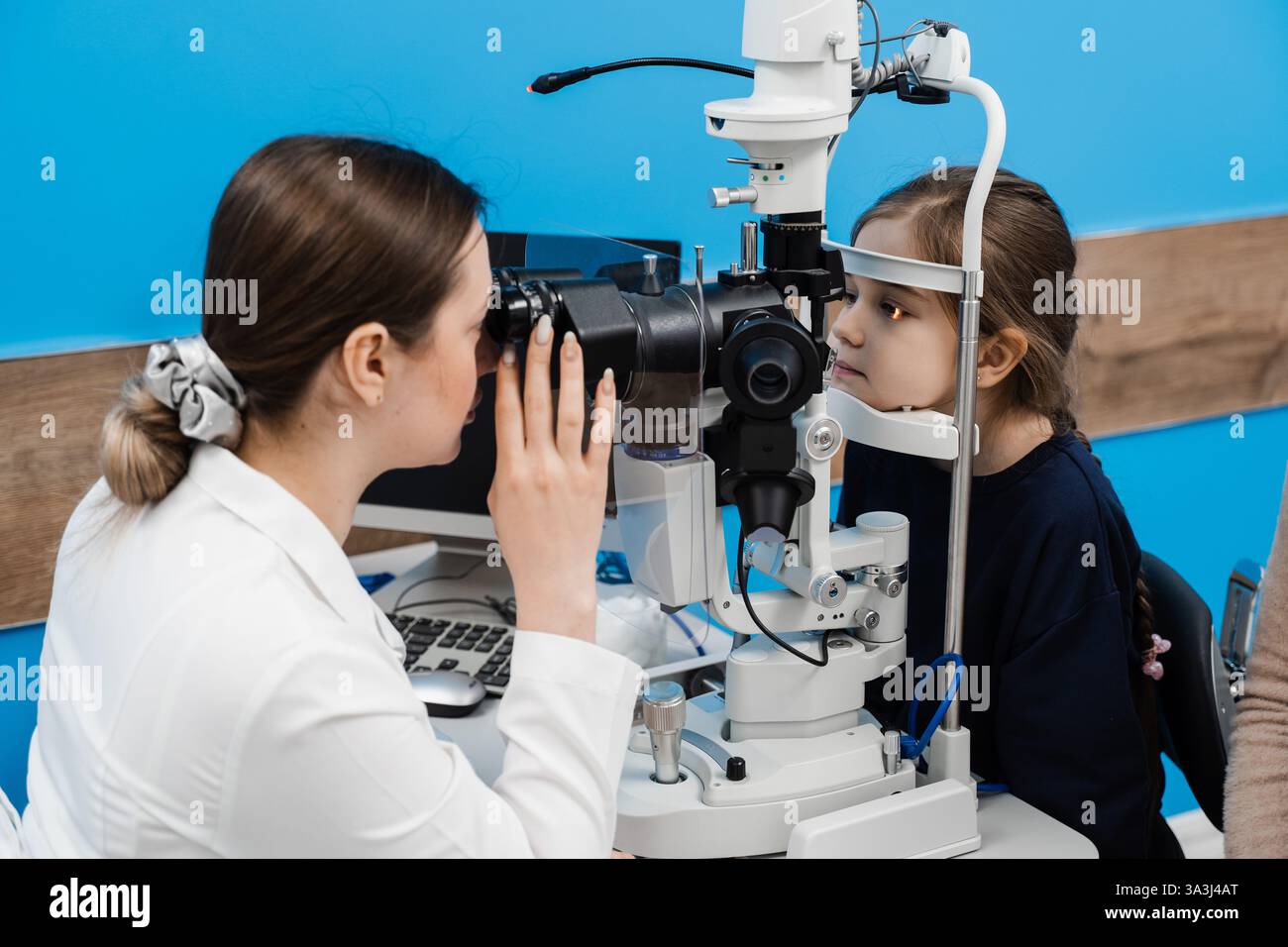 Ophthalmologist illuminates eye of child with light from slit lamp to ...