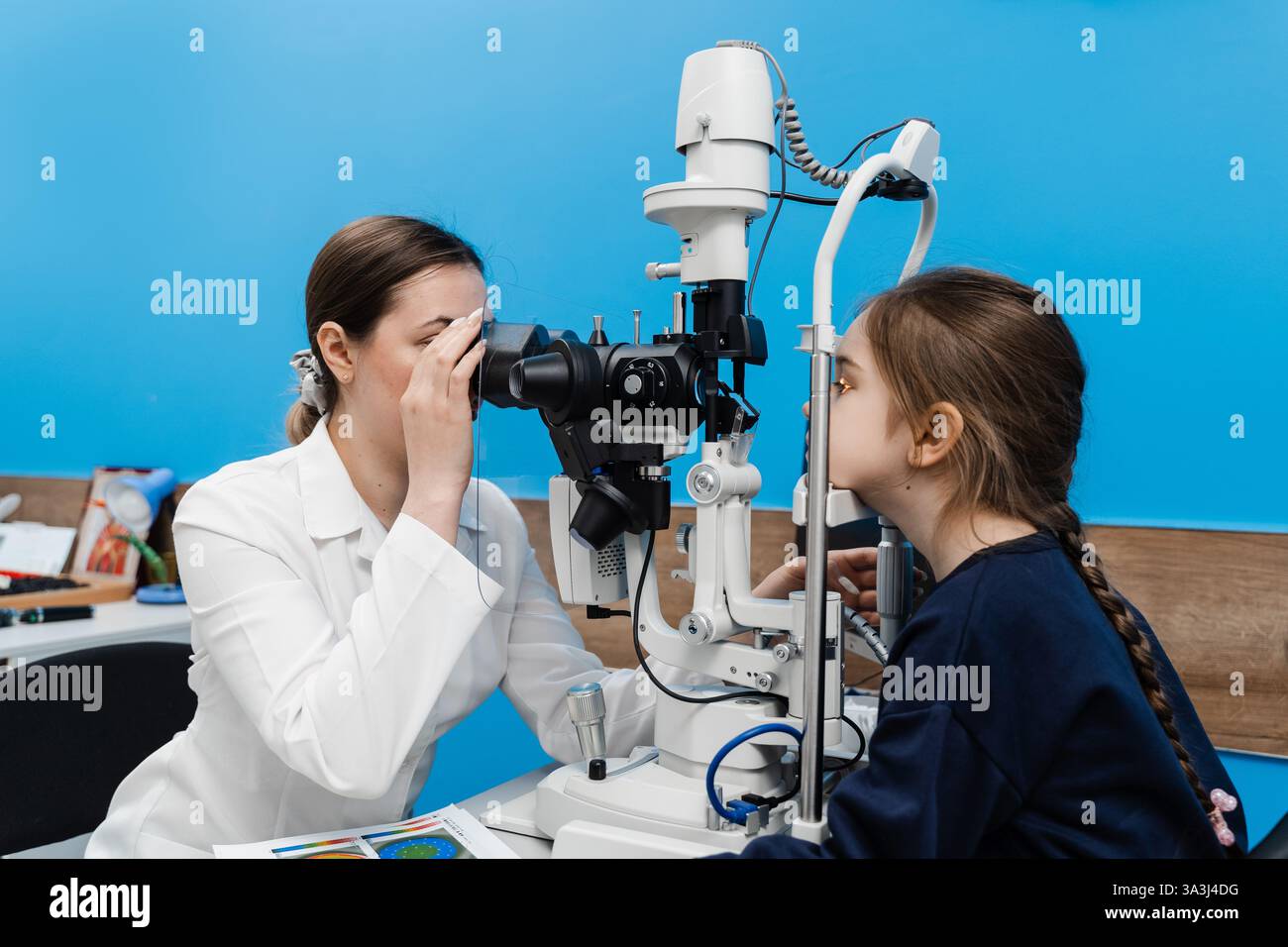 Pediatric ophthalmologist with slit lamp examines eyes and cornea of ...