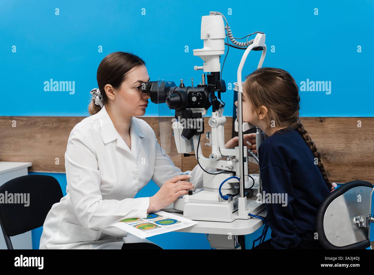 Ophthalmologist illuminates eye of child with light from slit lamp to ...