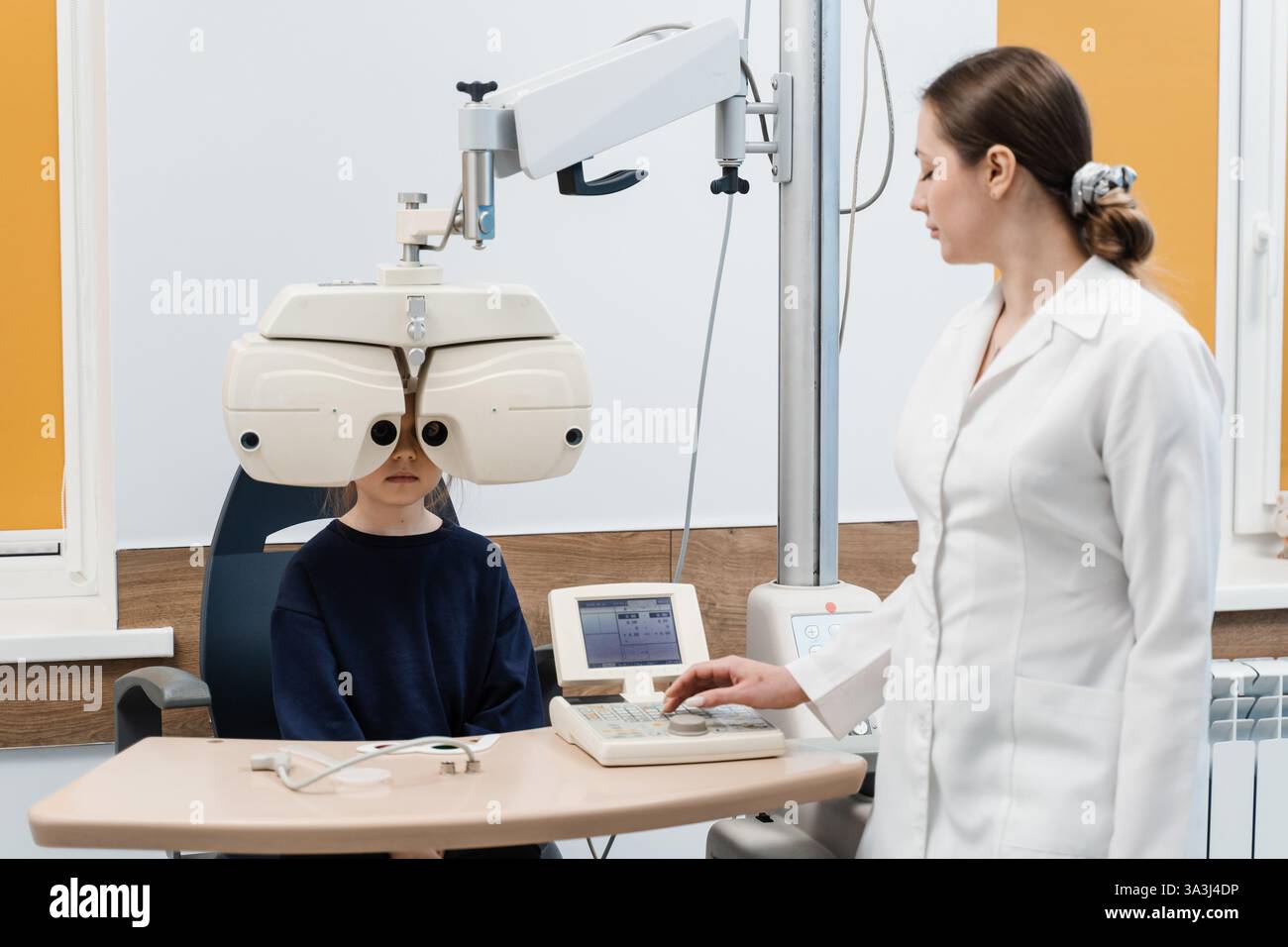 Child looks into phoropter during an eye examination of pediatric ...