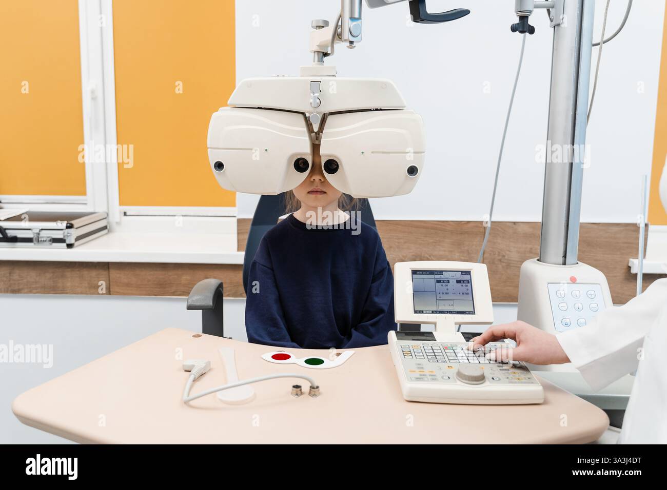 Child looks into phoropter during an eye examination of pediatric ...