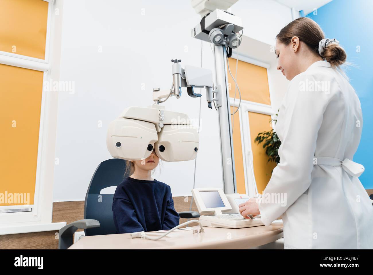 Child looks into phoropter during an eye examination of pediatric ...