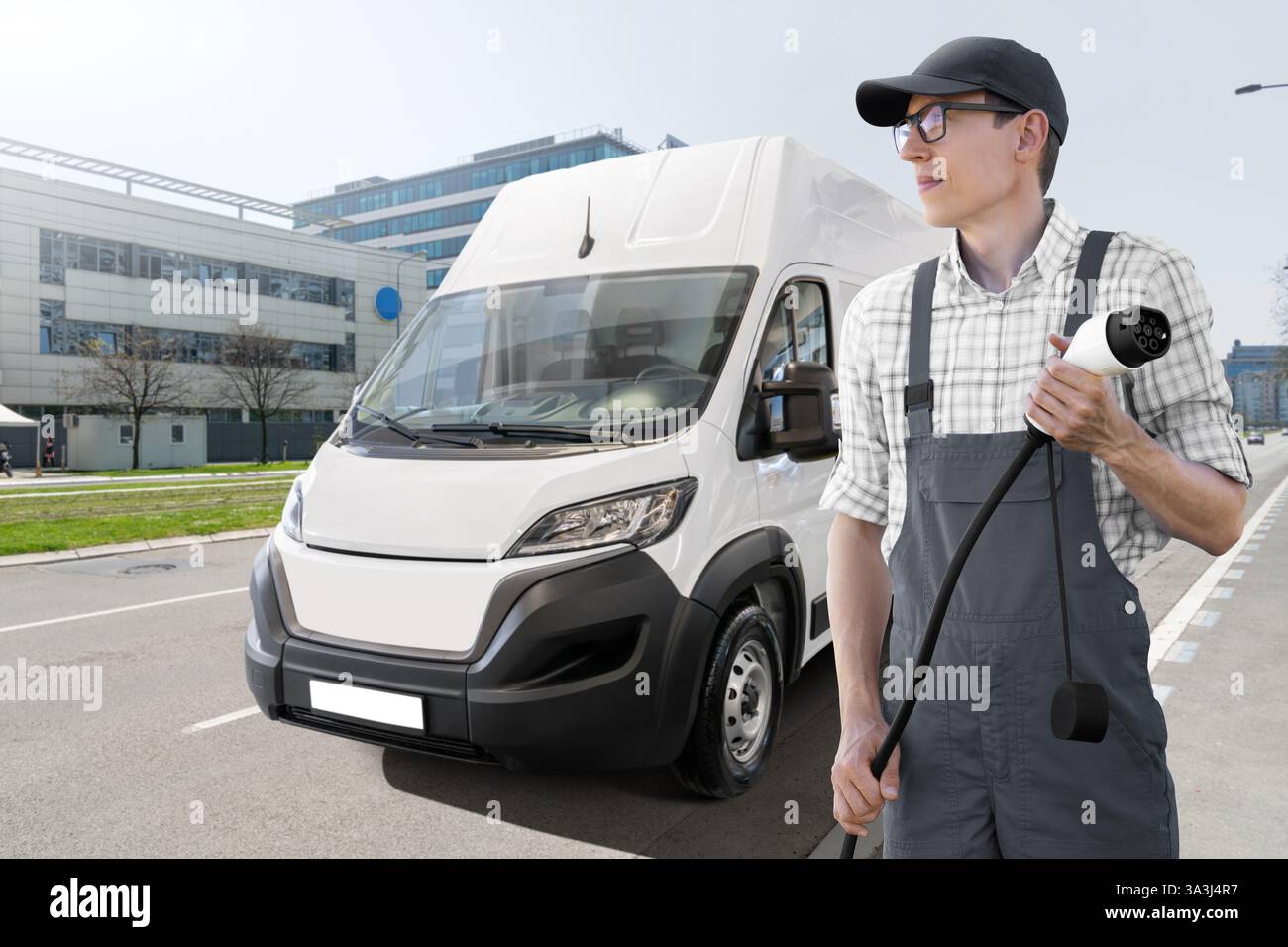 Man in uniform holds electric vehicle charging plug. Electric vans in ...