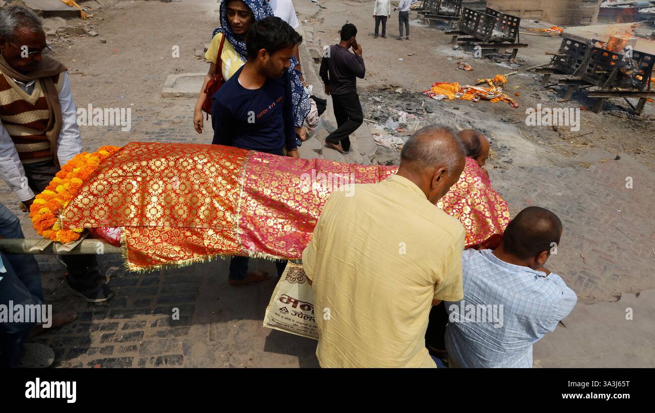 The shrouded body of a deceased person is carried to a funeral pyre on ...