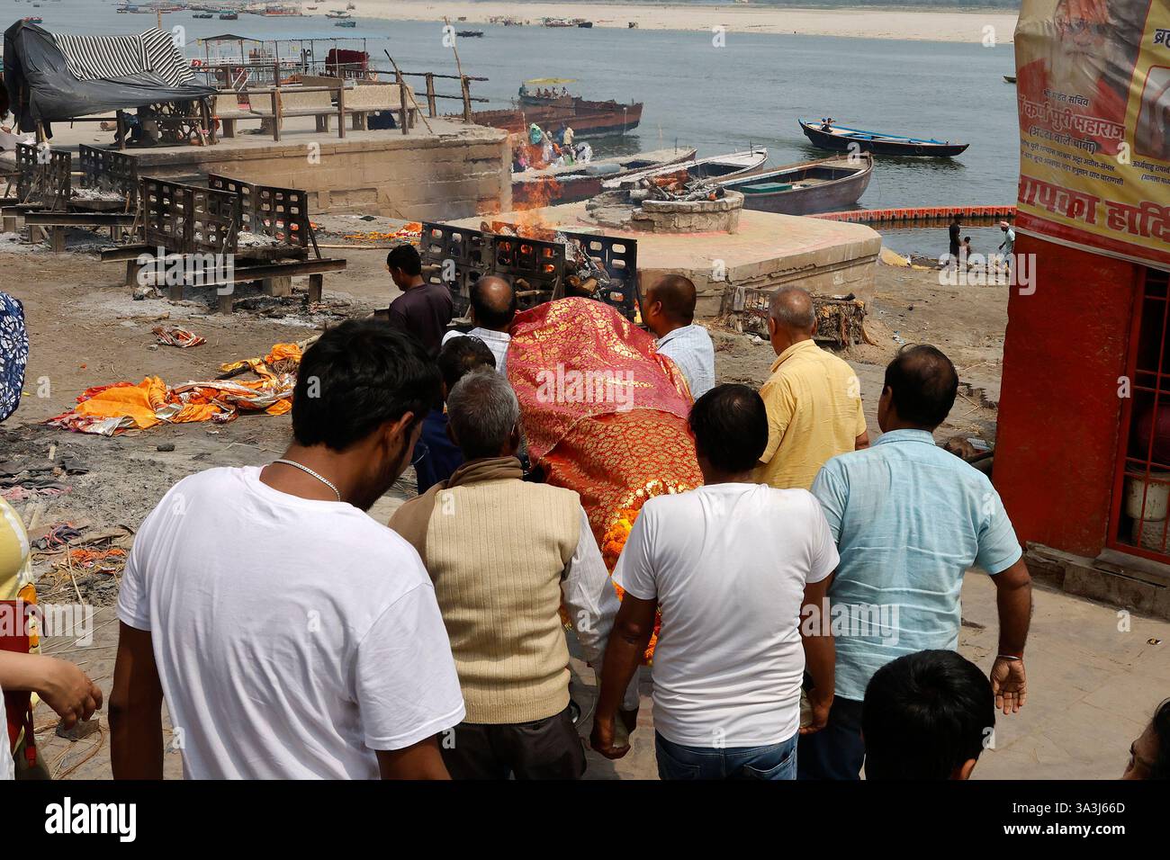 The shrouded body of a deceased person is carried to a funeral pyre on ...
