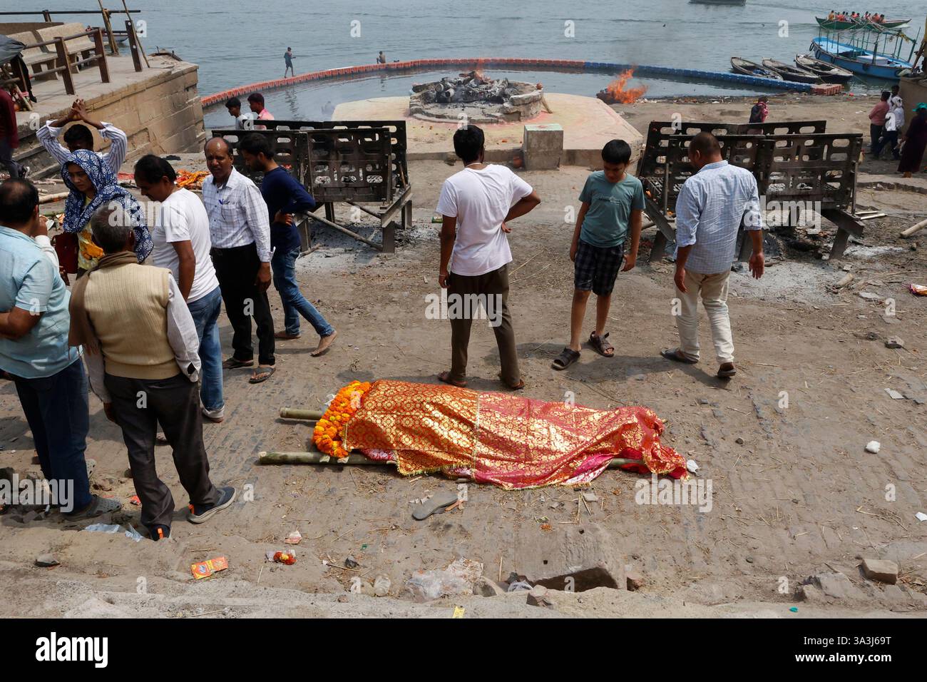 The shrouded body of a deceased person on the ground in front of ...