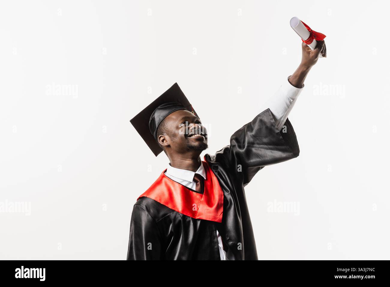 Happy african student in black graduation gown and cap raises masters ...