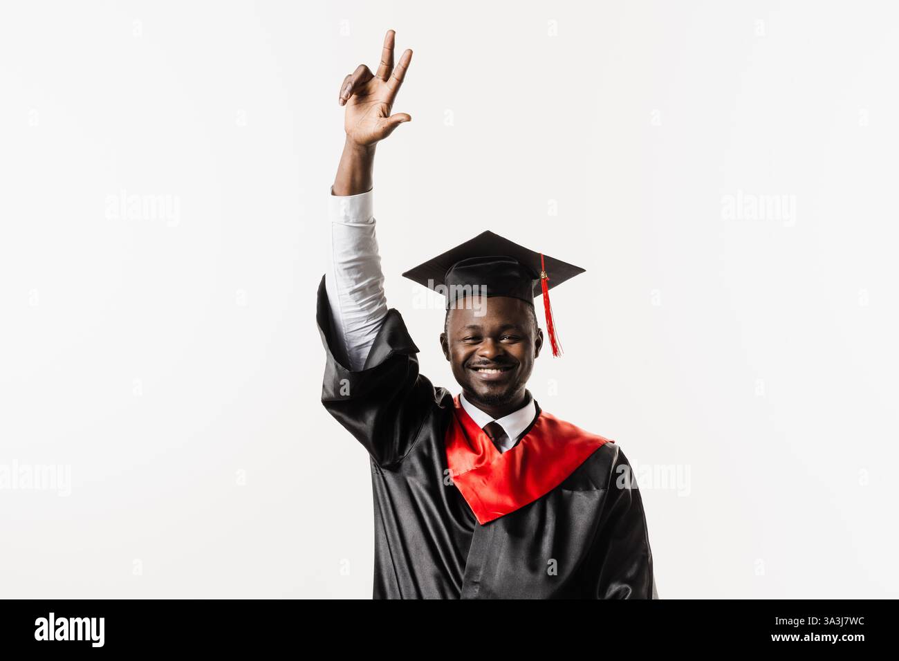 Happy african student in black graduation gown and cap raises his hands ...