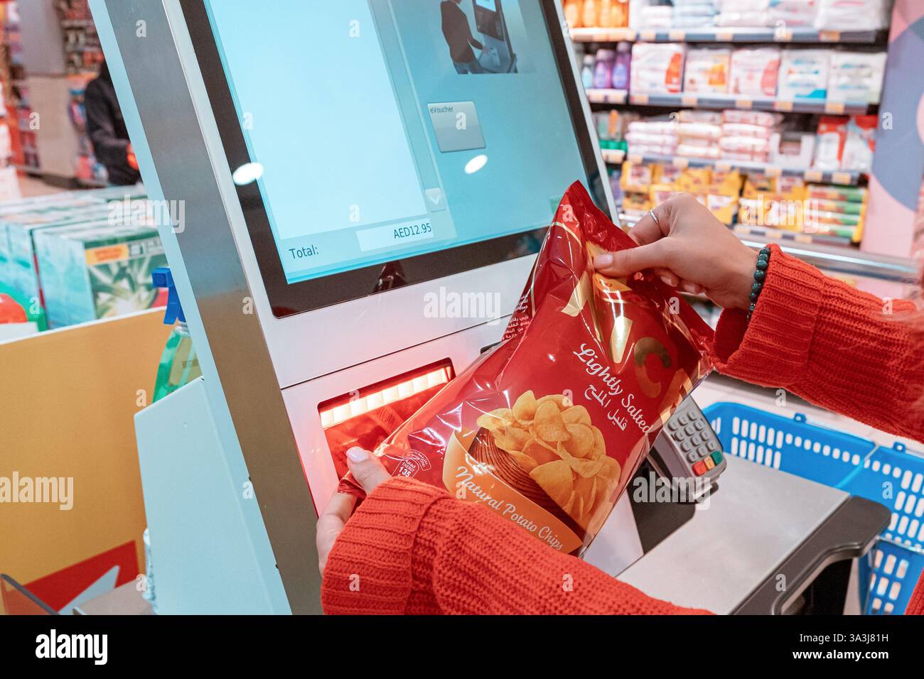 16 January 2025, Abu Dhabi, UAE: Woman scanning potato chips at a self ...