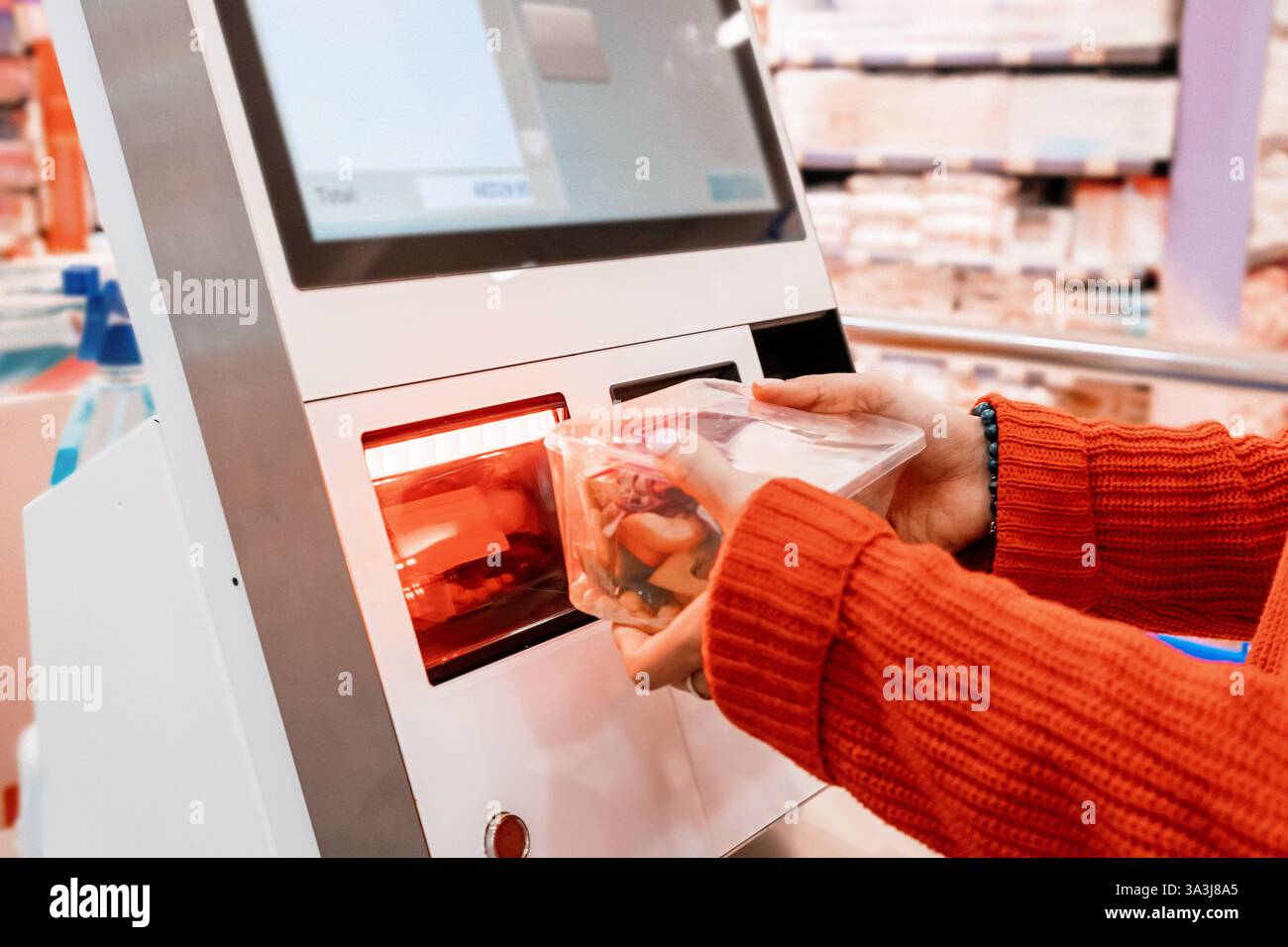 Woman scanning groceries at self checkout kiosk in modern supermarket ...