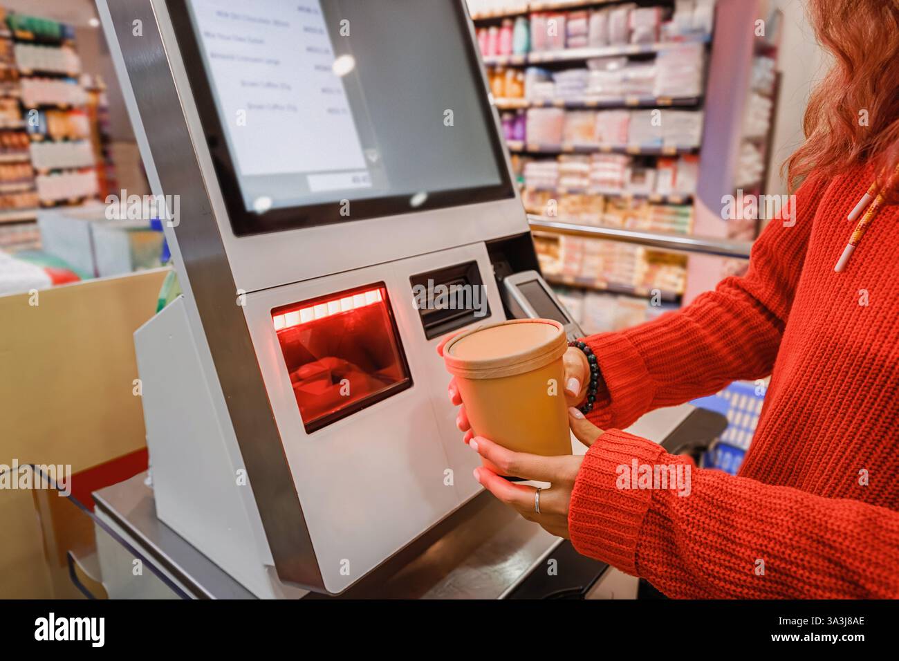 Woman scanning groceries at a self service checkout machine in a ...
