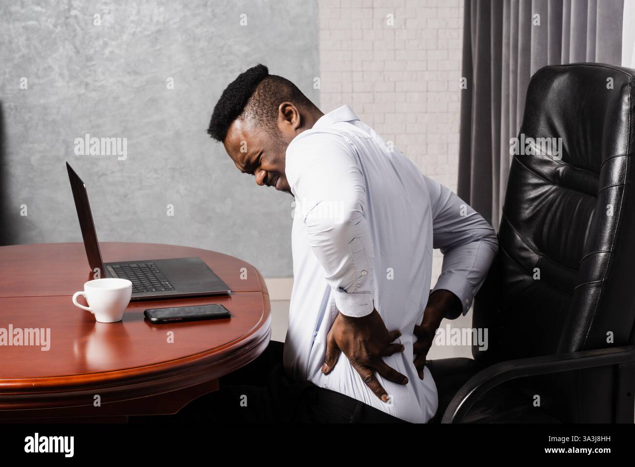 African man feels back pain after working for long hours with laptop ...