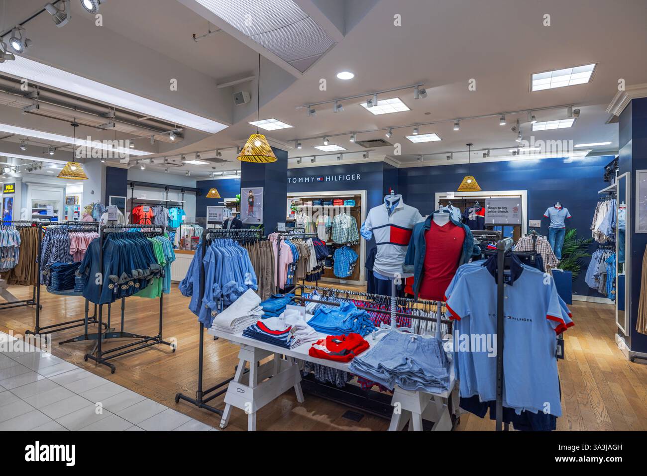 Tommy Hilfiger clothing section with polo shirts and casual outfits inside Macy's store. New ...