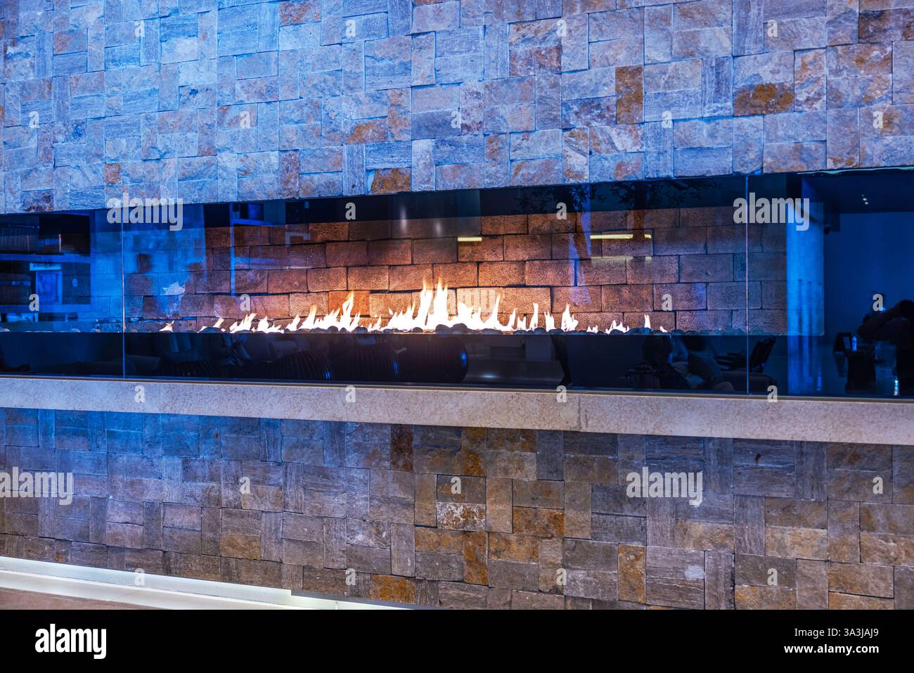 Modern gas fireplace with glass panel and stone wall in luxury hotel ...
