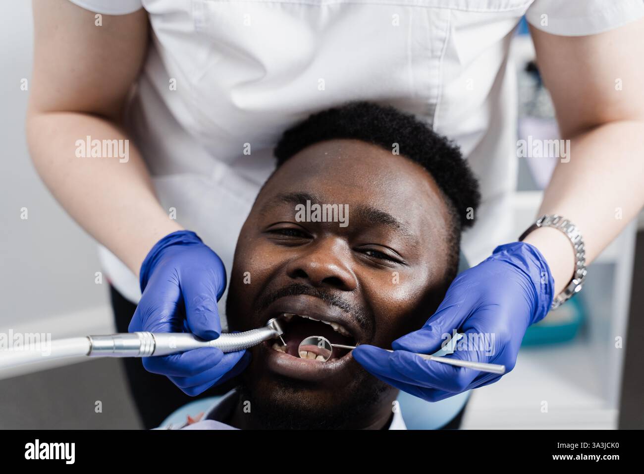 Dentist is drilling teeth and removing caries of african man in ...
