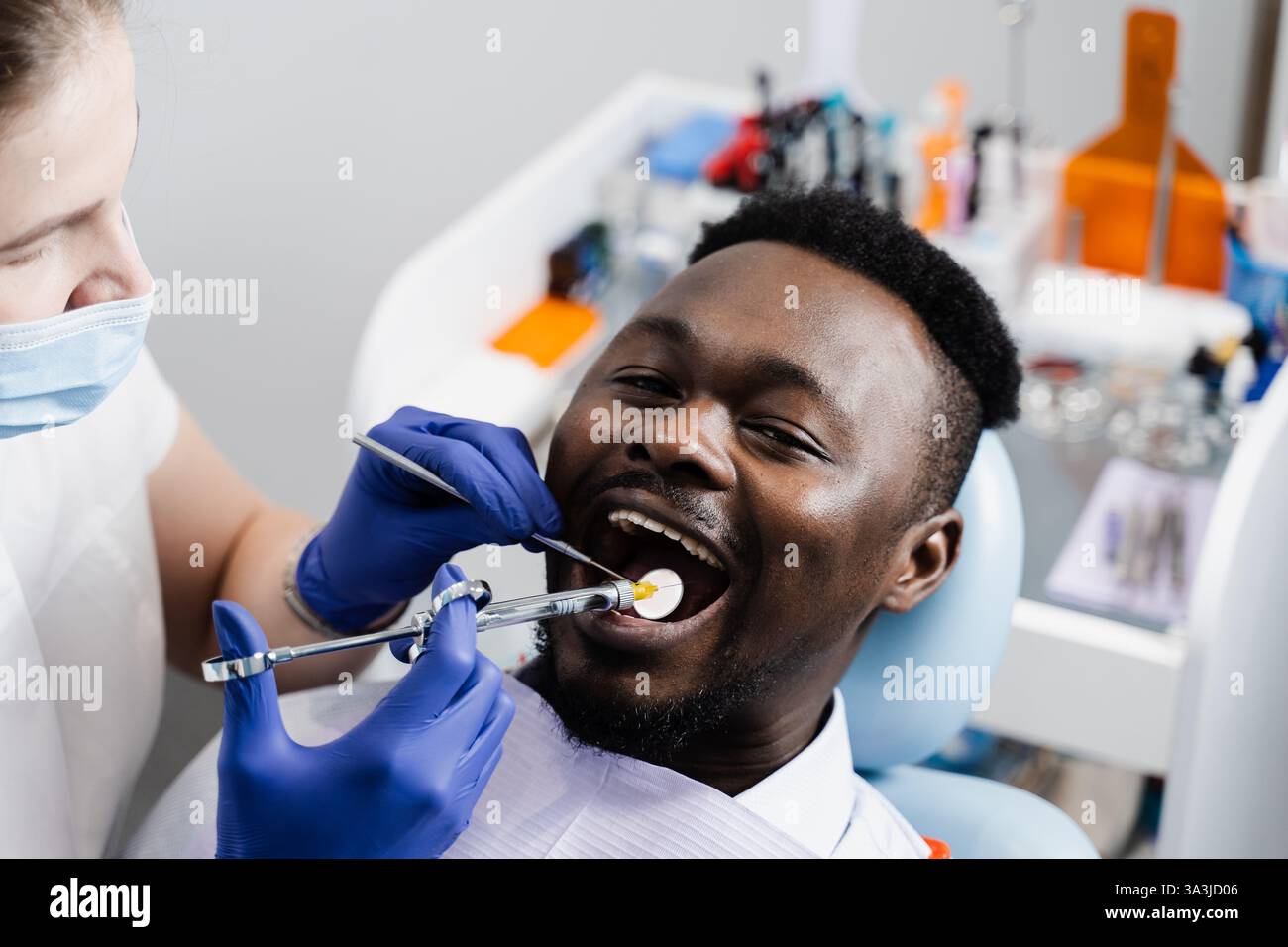 Dentist injects syringe with anesthesia in mouth of african man for ...