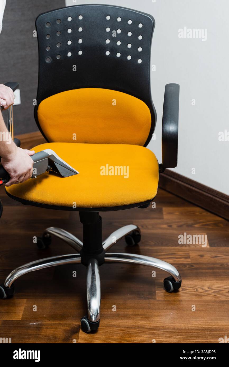 Domestic cleaning service cleaner is removing dirt and dust from chair ...