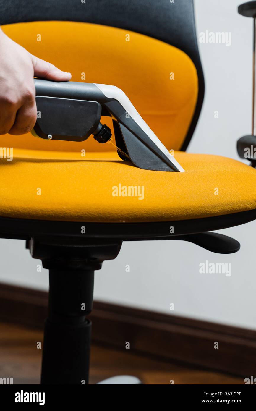 Housekeeper is extracting dirt from armchair using dry cleaning ...