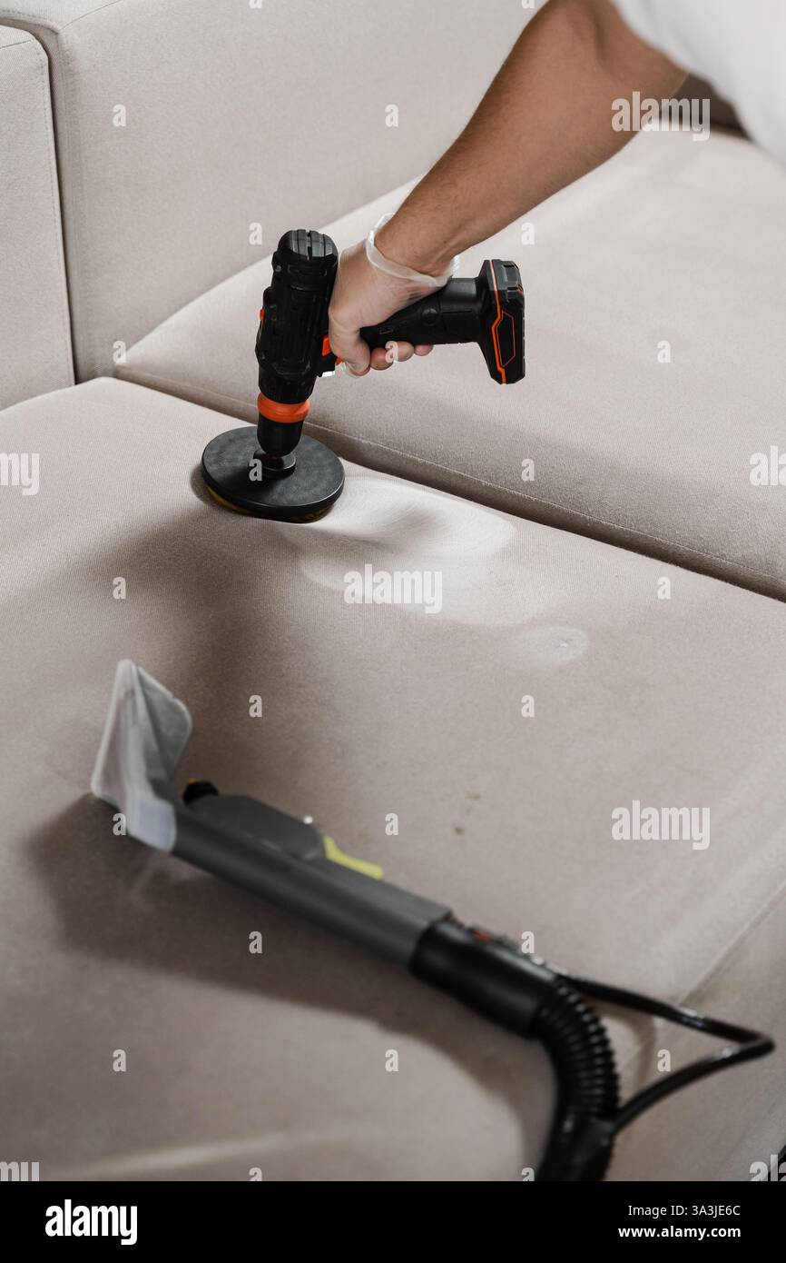 Smearing detergent on couch using drill with brush for dry cleaning ...