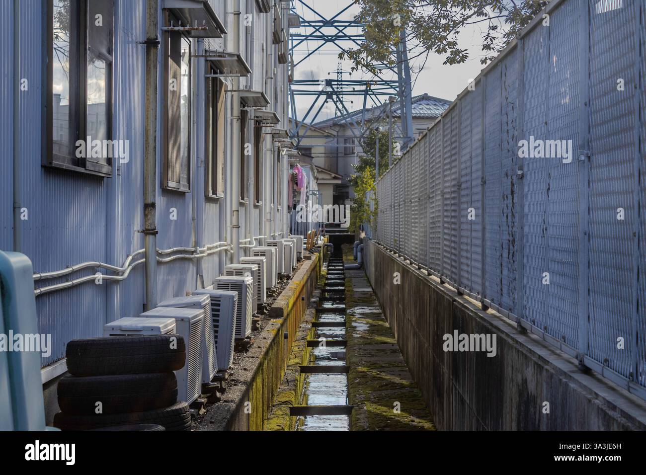 Narrow drainage alley behind houses, with outdoor units, Kanazawa ...