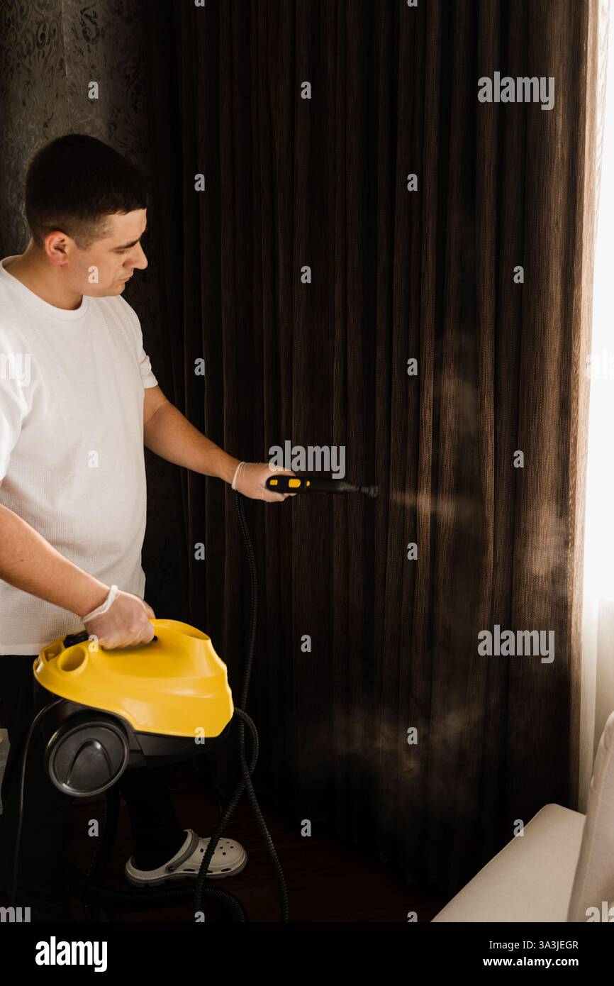 Cleaner is steaming the curtains using a professional steam machine ...