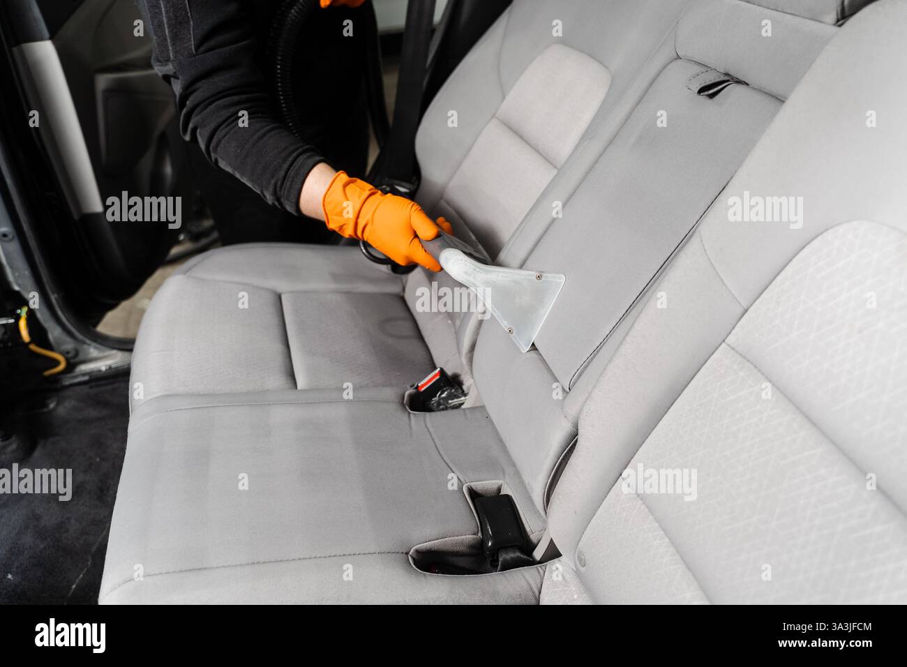 Cleaning textile seats in car interior using extractor machine for dry ...