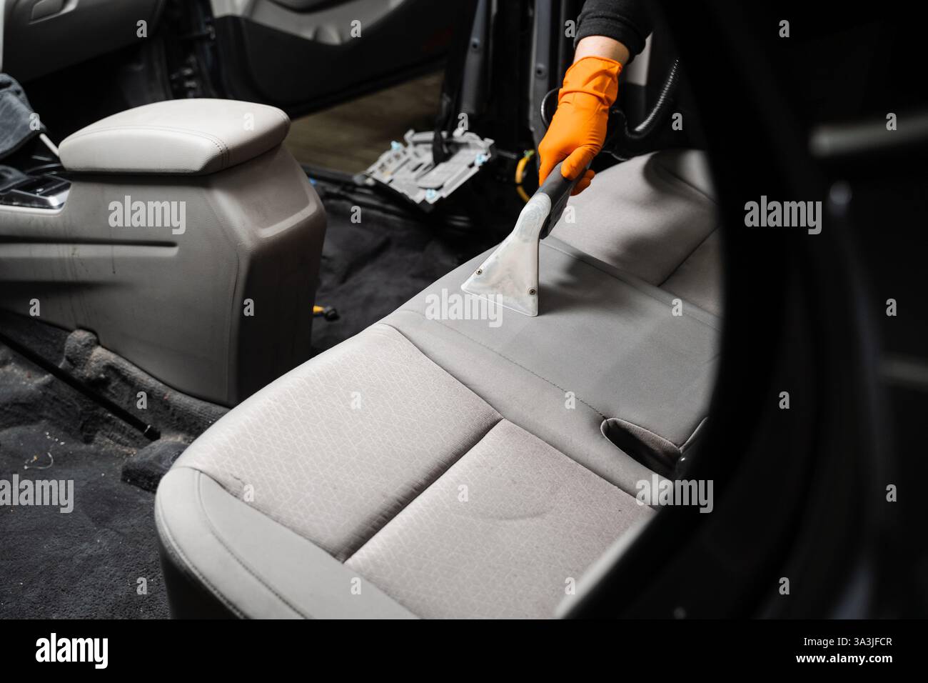 Cleaning textile seats in car interior using extractor machine for dry ...