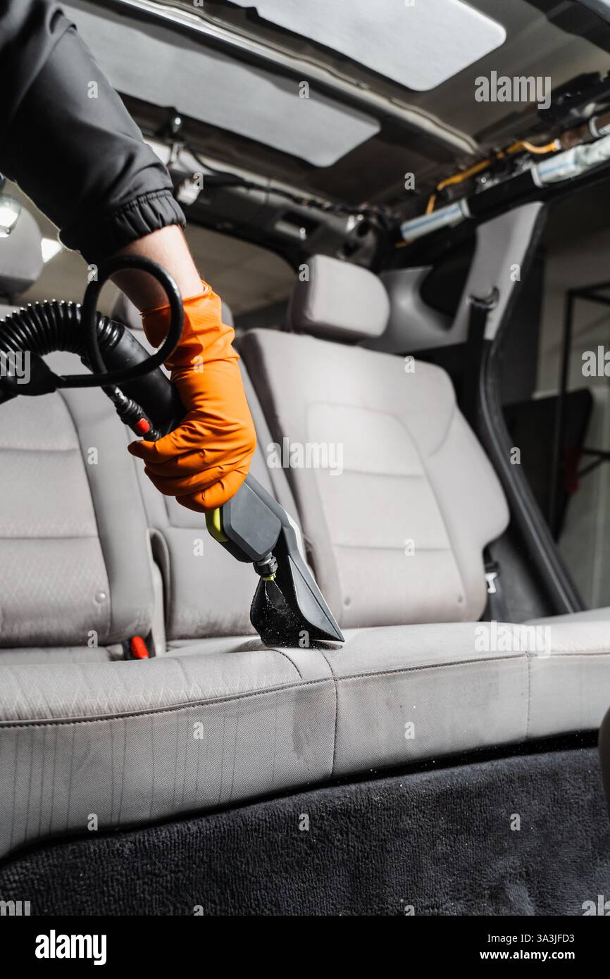 Car dry cleaner is using extraction machine for removing stains and ...