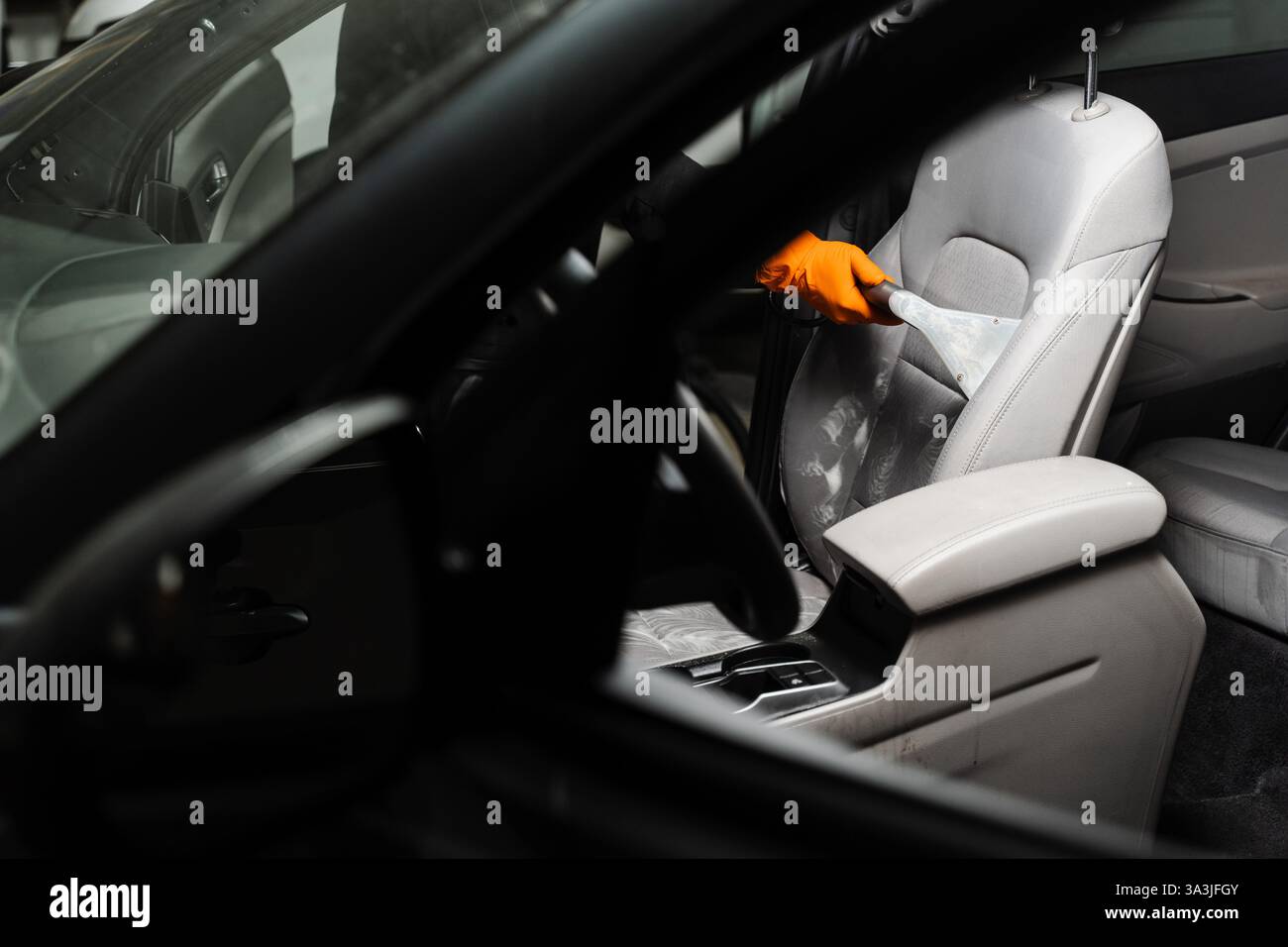 Cleaning textile seats in car interior using extractor machine for dry ...