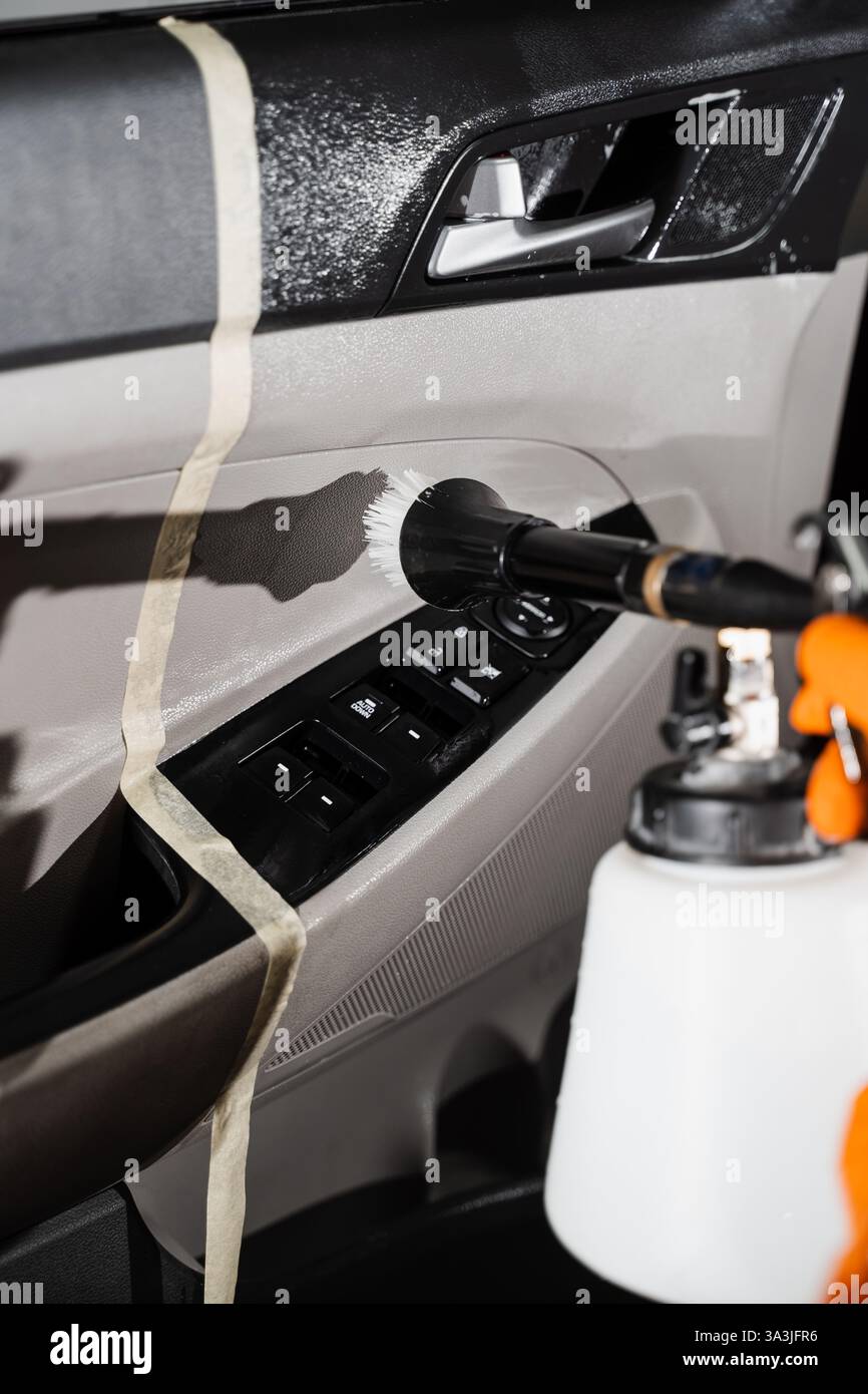 Car detailing with tornador cleaning gun with high pressure air pulse. Cleaner is washing car ...