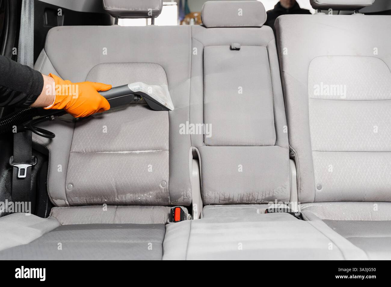 Cleaning textile seats in car interior using extractor machine for dry ...