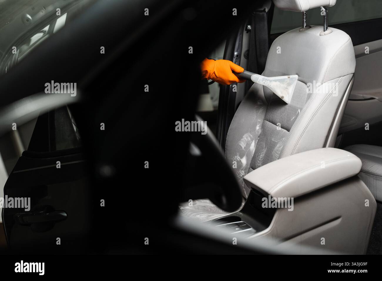 Cleaning textile seats in car interior using extractor machine for dry ...