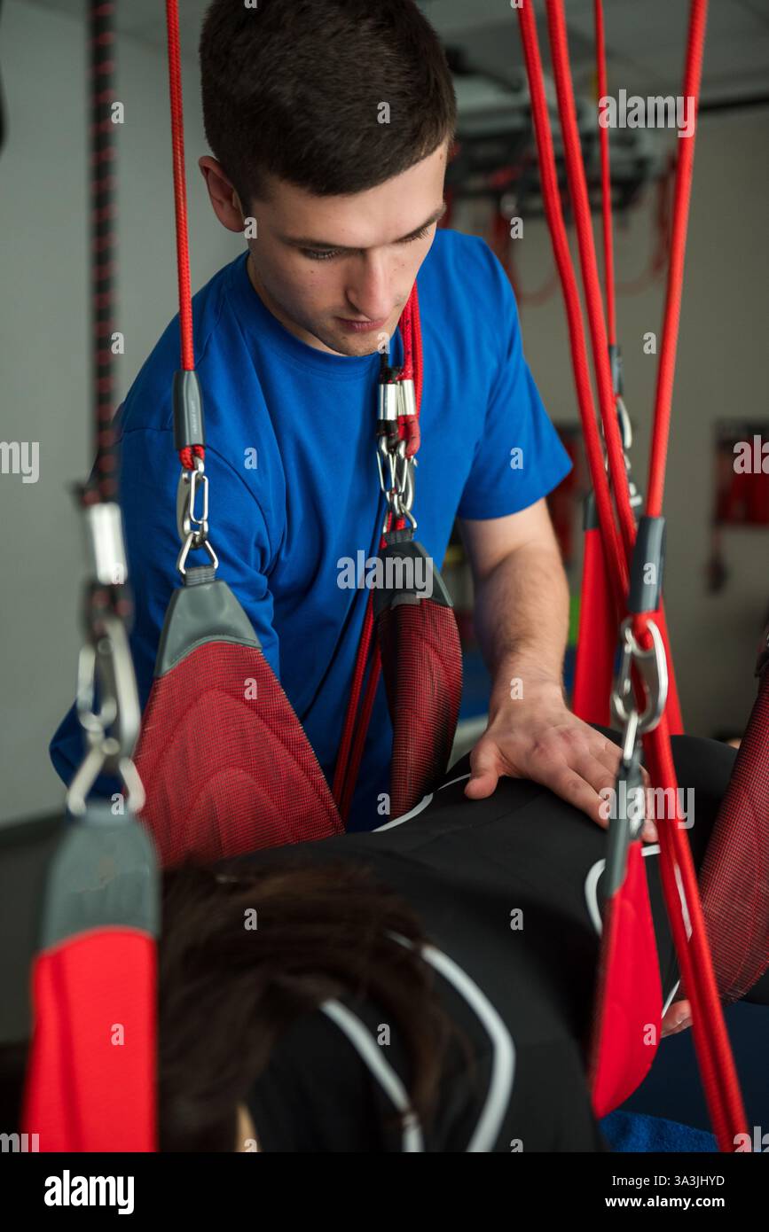 Assisting during red cord medical rehabilitation. Hanging on red straps ...