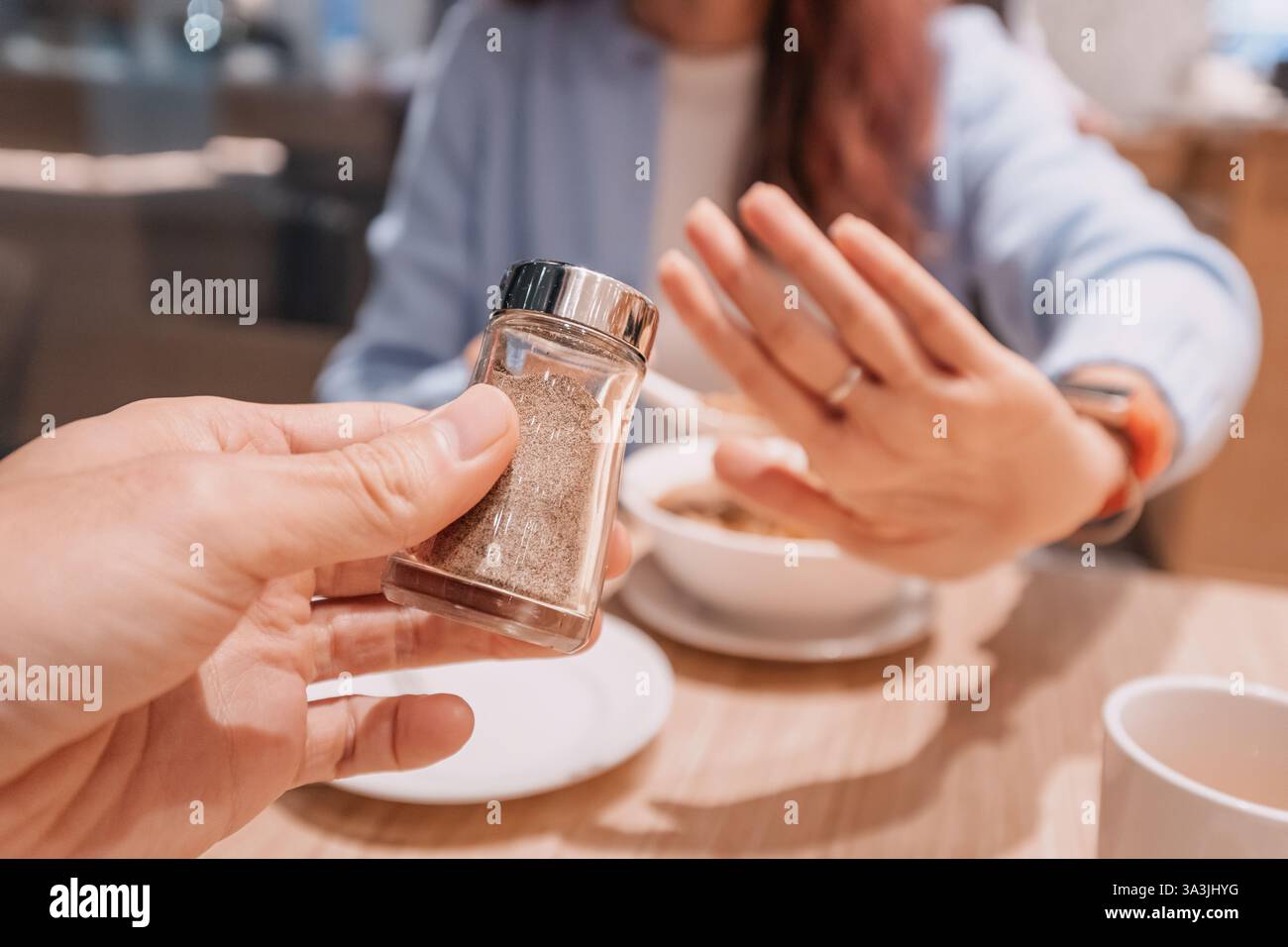 Woman making stop gesture with hand, refusing spices offered by waiter ...