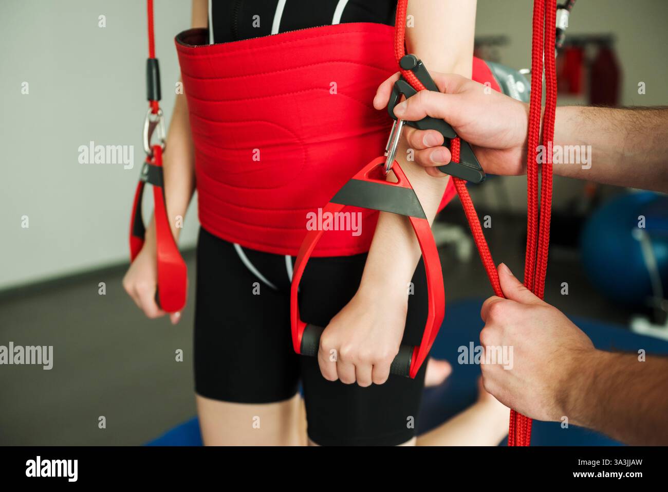 Assisting during red cord medical rehabilitation. Hanging on red straps ...