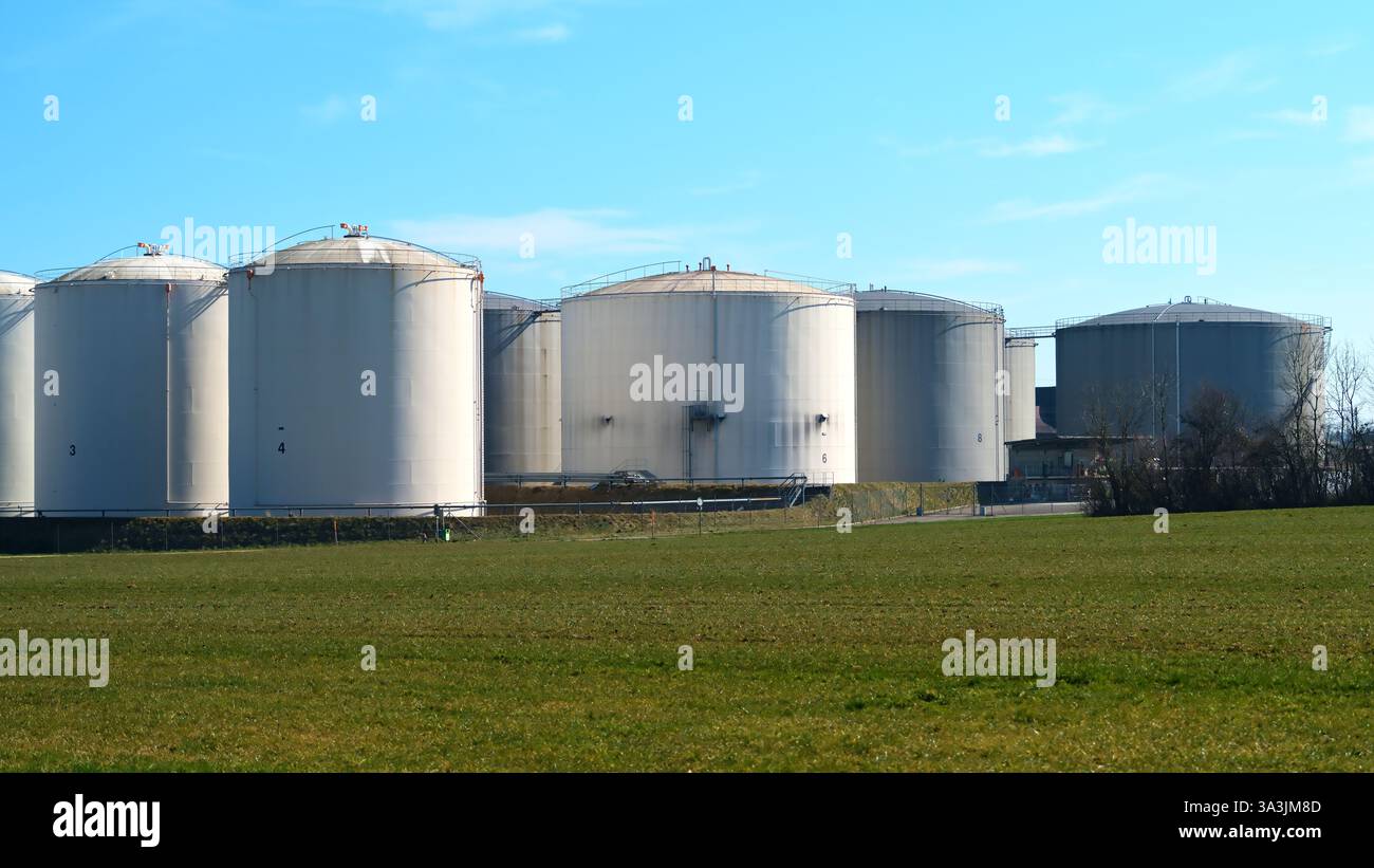 Multiple large storage silos standing in an open field under a clear ...